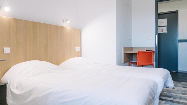 Quarto de hotel com cama, escrivaninha e cadeira.