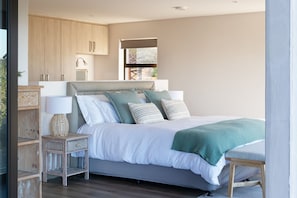 Quarto com cama, mesas de cabeceira, luminária e janela.