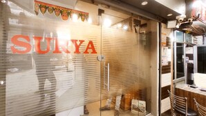 Restaurante com parede de vidro exibindo o nome 'SUNYA'.
