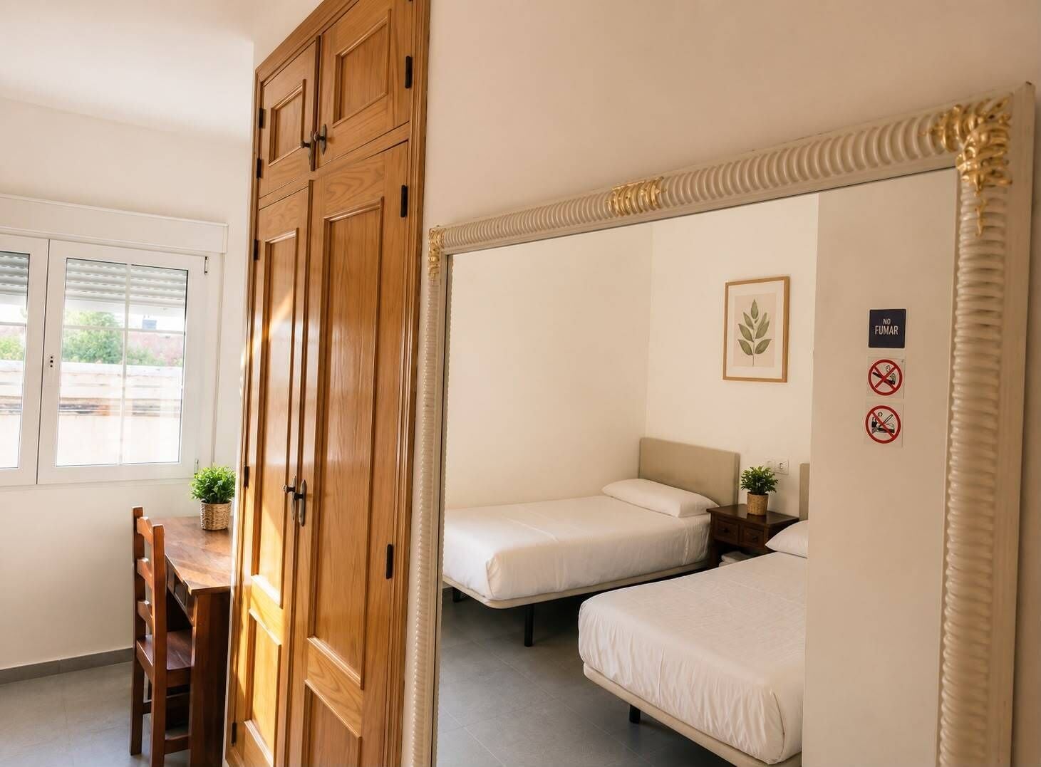 Quarto com guarda-roupa de madeira, duas camas, escrivaninha e cadeira, além de uma janela.
