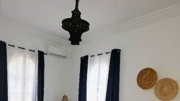 Quarto com cama, mesa de cabeceira, abajur e duas decorações de parede em tear.