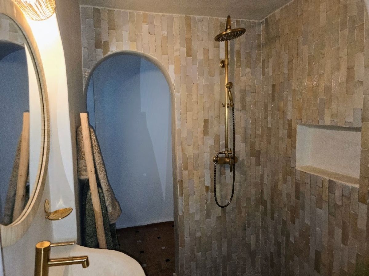 Casa de banho com chuveiro, porta-toalhas e espelho.