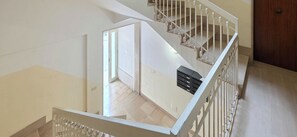 Interior com vários níveis, uma escada, uma porta e um respiradouro na parede.