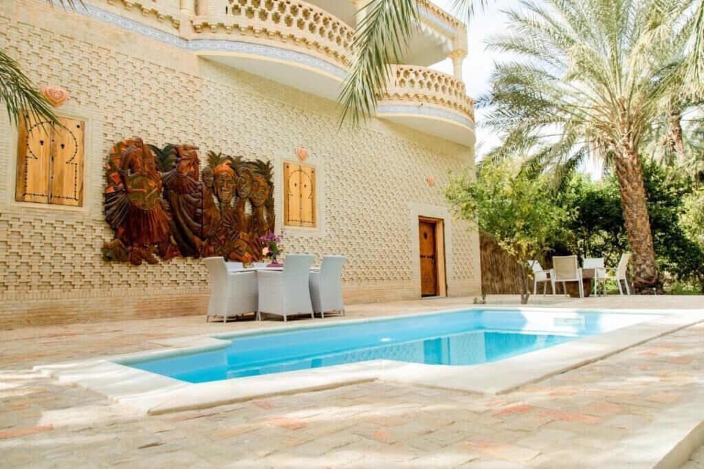 Uma área à beira da piscina com parede de tijolos, painéis decorativos e assentos externos.