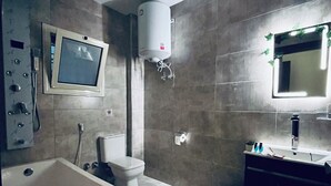 Uma casa de banho moderna com banheira, sanita, lavatório e espelho com luzes.