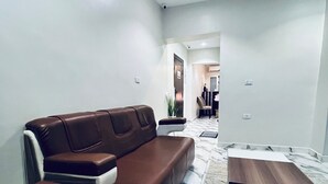 Uma sala de estar moderna com um sofá de couro marrom, uma poltrona branca e um banquinho combinando.