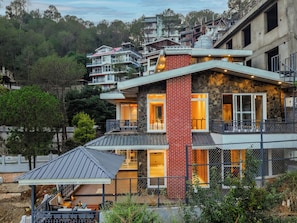 Uma casa de vários andares com fachada de pedra, várias varandas e uma área coberta para relaxar ao ar livre.