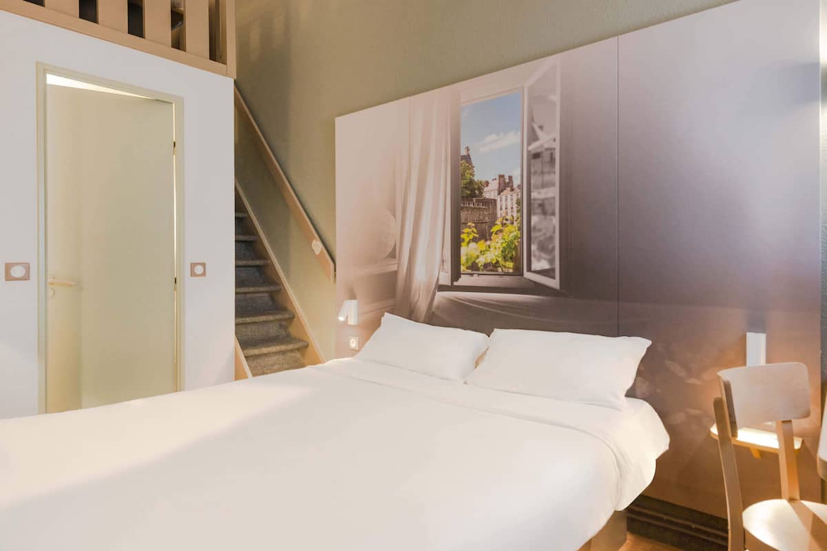 Quarto com cama, janela com cortinas, escada e luminária fixada na parede.