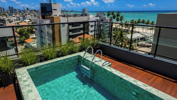 Piscina no terraço com vista para a cidade e praia.