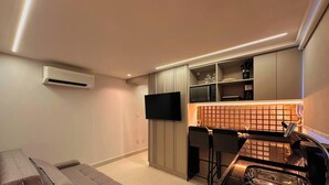 Uma cozinha moderna com televisão de tela plana, armários embutidos e área de bar com banquetas.