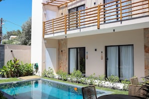 Um hotel moderno com piscina, área externa para sentar e varanda.