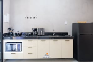 Uma cozinha moderna com micro-ondas, torradeira, chaleira e pia.