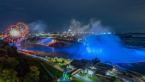 Hotel à beira-mar com vista para uma cascata, uma ponte e fogos de artifício.