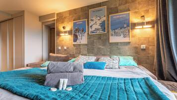 Quarto de hotel com uma cama grande, um cobertor azul e três posters emoldurados na parede.
