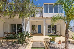 Uma casa moderna com um pátio, área de estar externa e plantas em vasos.