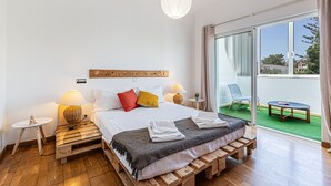 Quarto com cama, mesas de cabeceira, luminária, vista para o exterior e um aviso na parede.