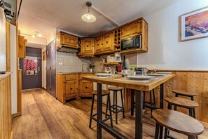 Uma cozinha compacta com armários de madeira, um micro-ondas e banquetas.
