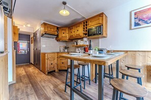 Uma cozinha compacta com armários de madeira, micro-ondas e área de refeições com banquetas.