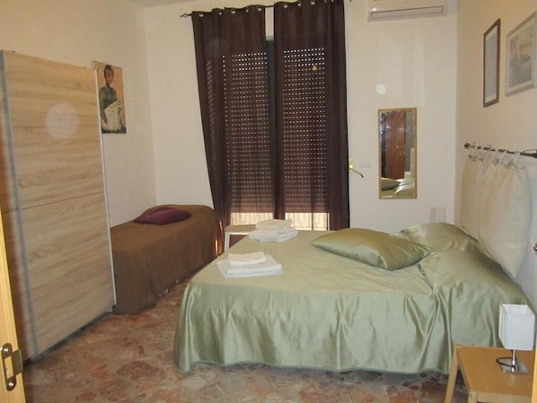 Quarto com cama, cadeira, guarda-roupa e janela com cortinas.