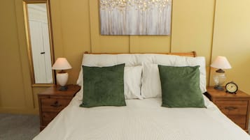 Um quarto com cama, duas mesas de cabeceira, um espelho, um quadro e um relógio.