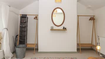 Quarto com cama, cadeira suspensa, prateleira com objetos, espelho, luminária e radiador.