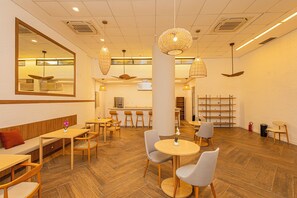 Interior de restaurante com mobiliário de madeira, iluminação pendente e um espelho na parede.