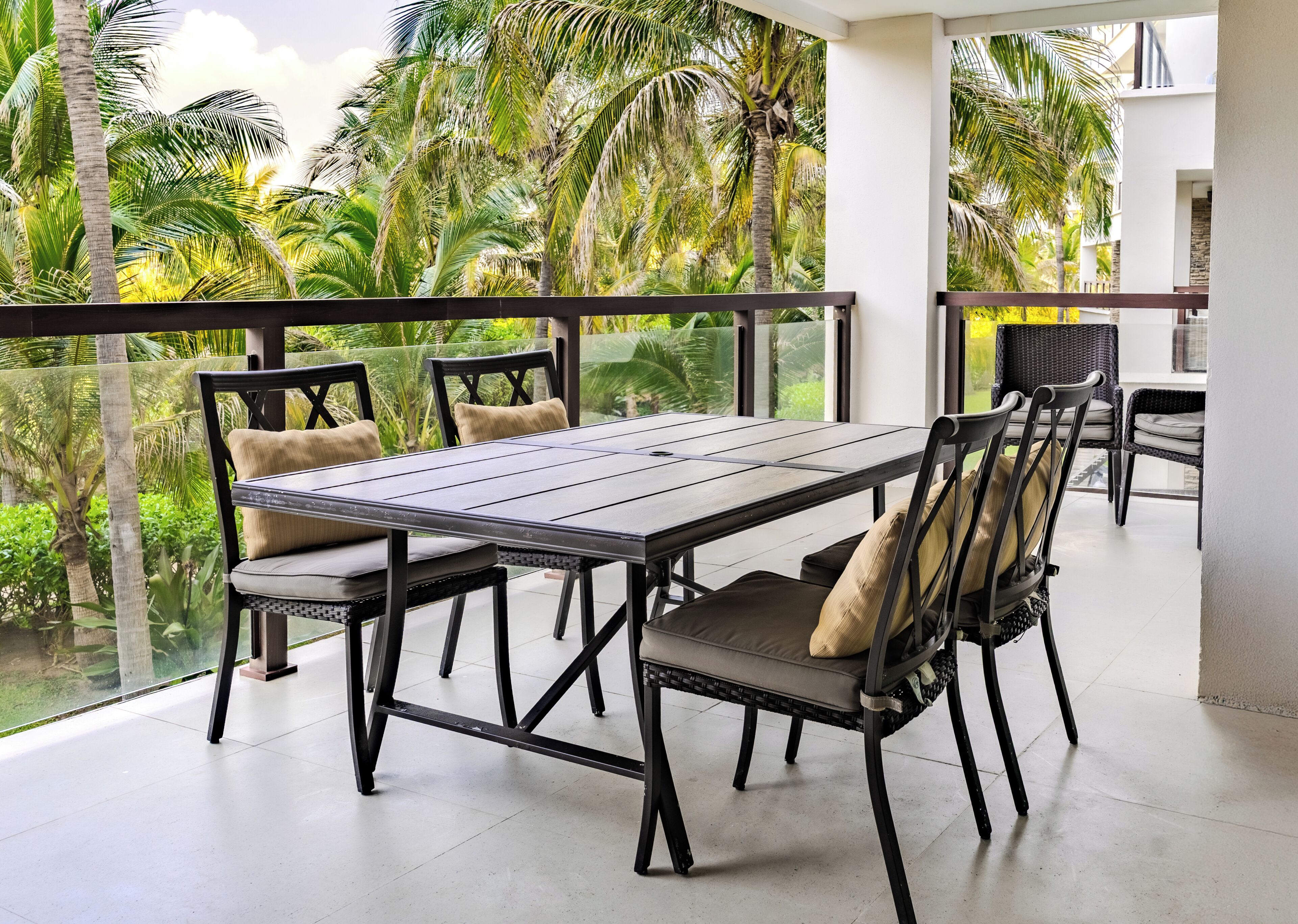 Uma varanda com mesa e cadeiras, com vista para um jardim tropical.