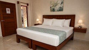 Uma cama bem arrumada com colcha estampada, cabeceira de madeira, duas mesas de cabeceira com abajures e uma obra de arte na parede.