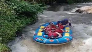 Um grupo de pessoas em uma jangada inflável azul navegando em um rio.