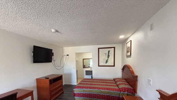 Quarto de hotel com duas camas, televisão, escrivaninha e cómoda.
