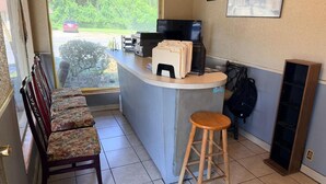 Uma pequena cozinha compacta com bancada, um banco de madeira e vista para o exterior.