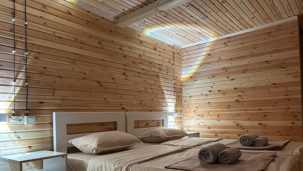 Quarto com painéis de madeira, cama, mesas de cabeceira e um claraboia.