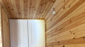 Uma pequena cabana de madeira com cozinha compacta, incluindo armários e bancada.