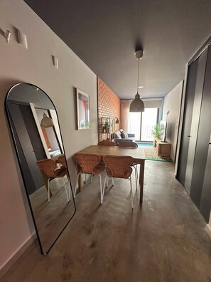 Uma sala de estar moderna com área de jantar, um espelho grande e uma parede de destaque em tijolo.