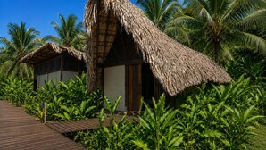 Uma cabana com telhado de palha e varanda de madeira, cercada por vegetação tropical exuberante.