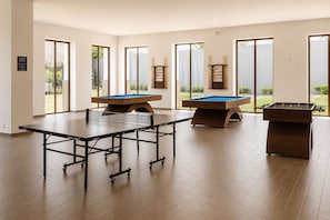 Um quarto espaçoso com mesa de pingue-pongue, mesa de futebol de mesa e mesa de bilhar.
