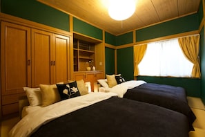 Quarto com duas camas, guarda-roupa de madeira e janela com cortinas.
