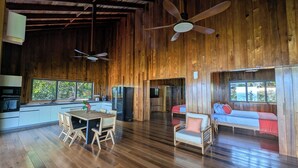 Um quarto amplo com paredes de madeira, área de refeições, sofá e ventoinha no teto.
