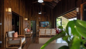 Interior de madeira com ventiladores de teto, televisão e áreas de estar.