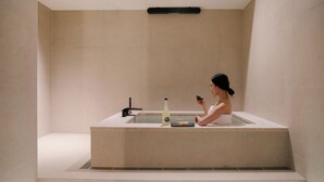 Uma casa de banho moderna com banheira, garrafa e toalha.
