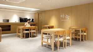 Quarto de hotel com móveis de madeira, cozinha compacta e uma placa com a inscrição 'ANOOK HOTEL'.