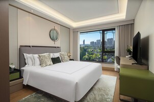 Quarto de hotel moderno com uma cama grande, uma escrivaninha, uma televisão e vista para a cidade.