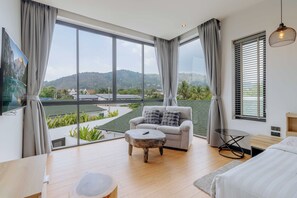 Um quarto moderno com uma grande janela, um sofá, uma mesa de centro redonda e uma cama.