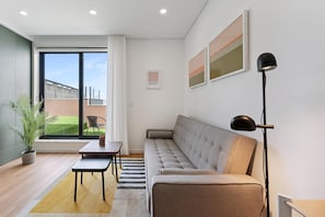 Uma sala de estar moderna com um sofá, uma mesinha, um abajur e um vaso de planta.