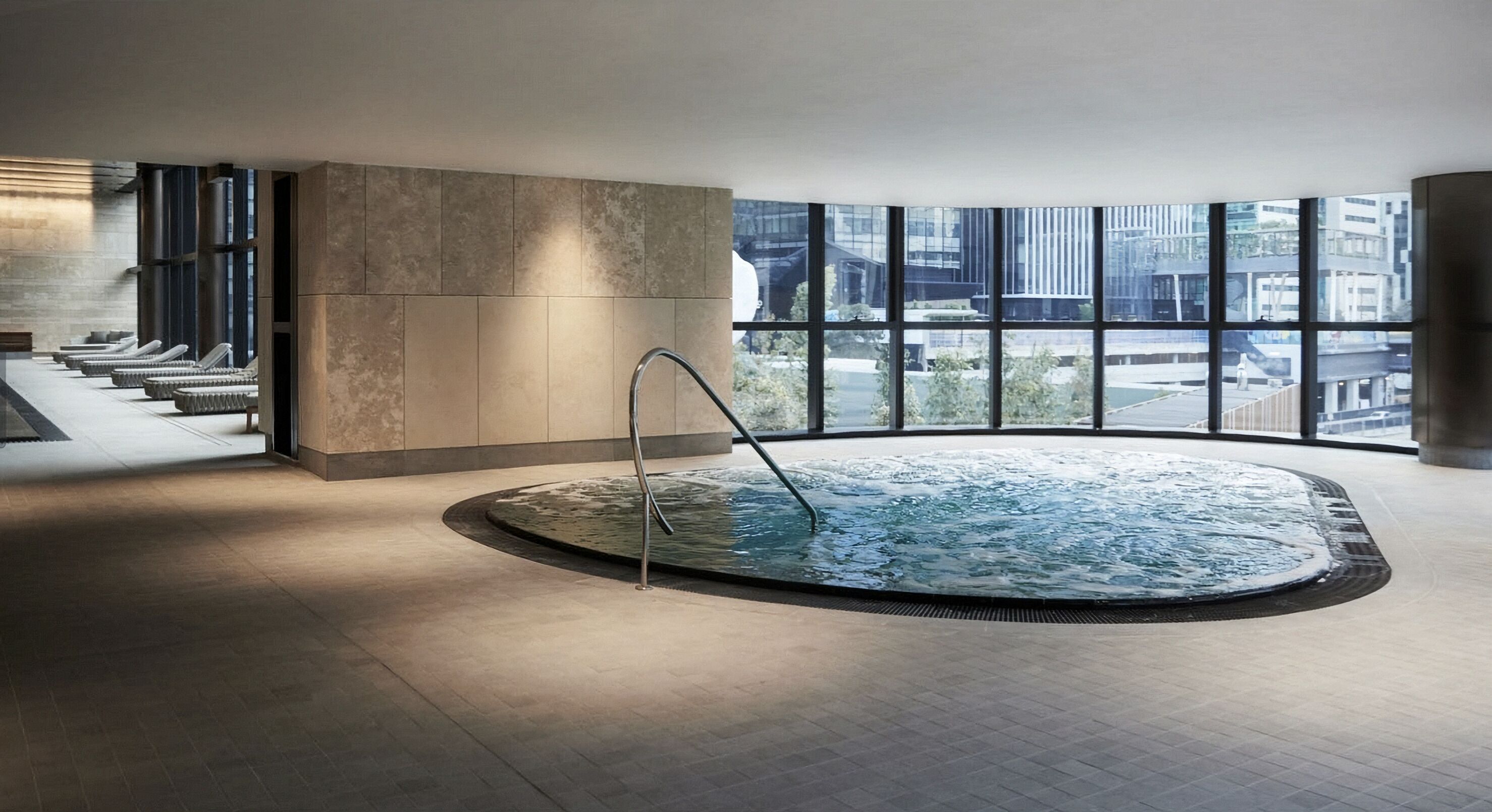 Piscina interior moderna com vista clara para o horizonte urbano através de amplas janelas.