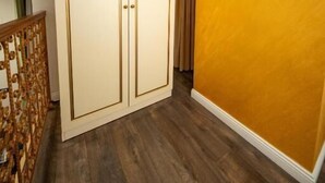 Um quarto com piso de madeira, guarda-roupa branco e parede amarela.