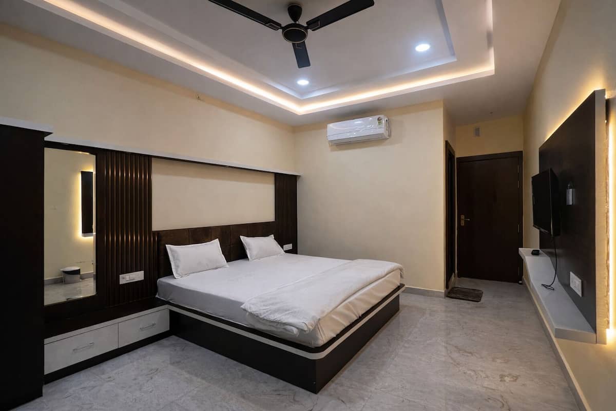 Quarto moderno com cama, ventilador de teto, ar-condicionado, televisão e espelho.