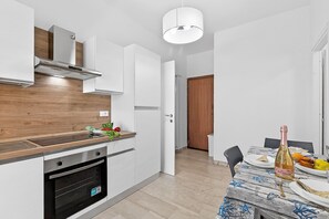 Cozinha moderna com forno embutido, bancada de madeira e área de refeições com mesa posta para dois.