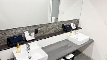 Um banheiro moderno com duas pias, um espelho grande e um porta-toalhas.