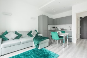 Uma sala de estar moderna com sofá, mesa de jantar e área de cozinha.